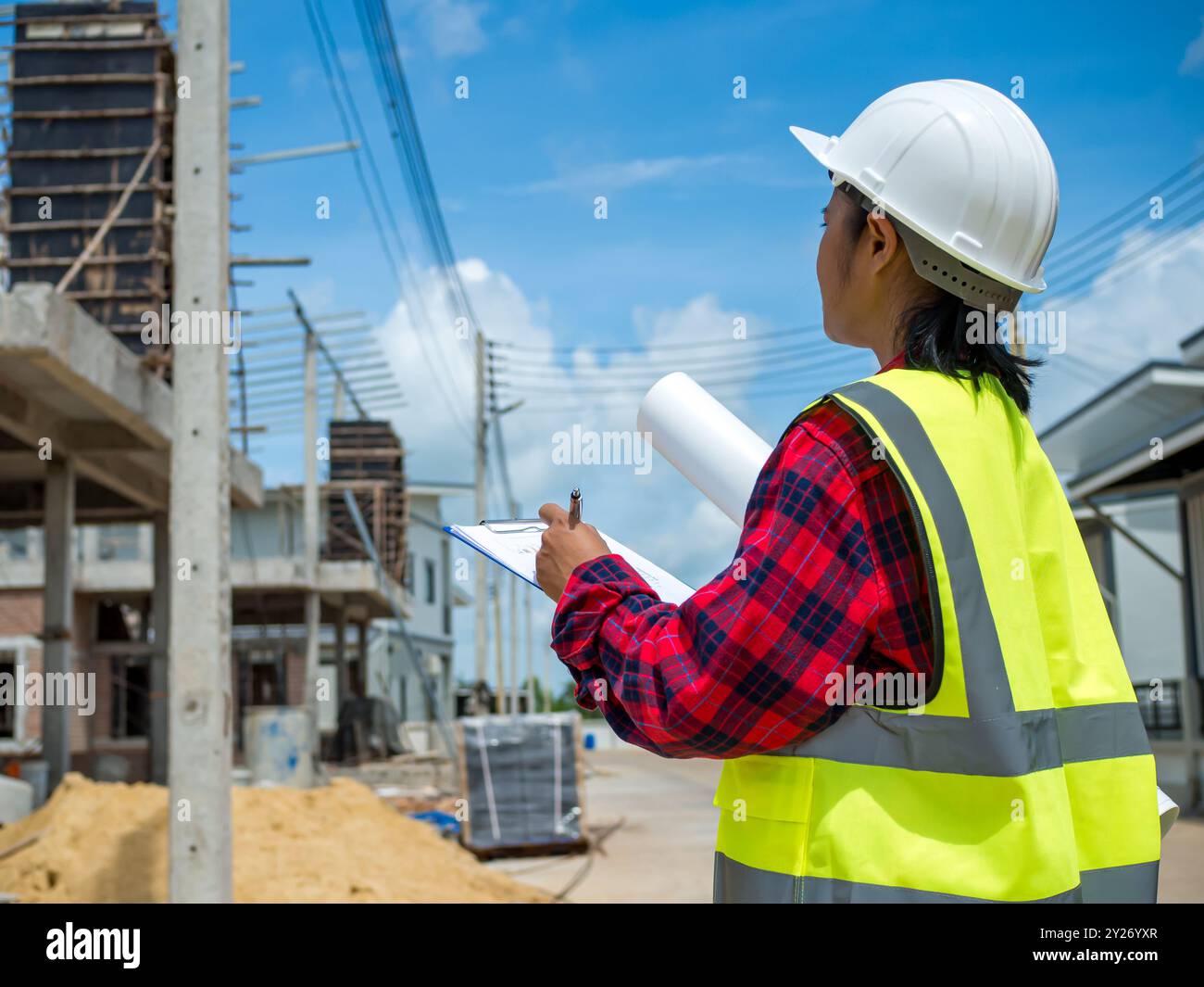 Engineers holding blueprint project working outdoors building side with ...
