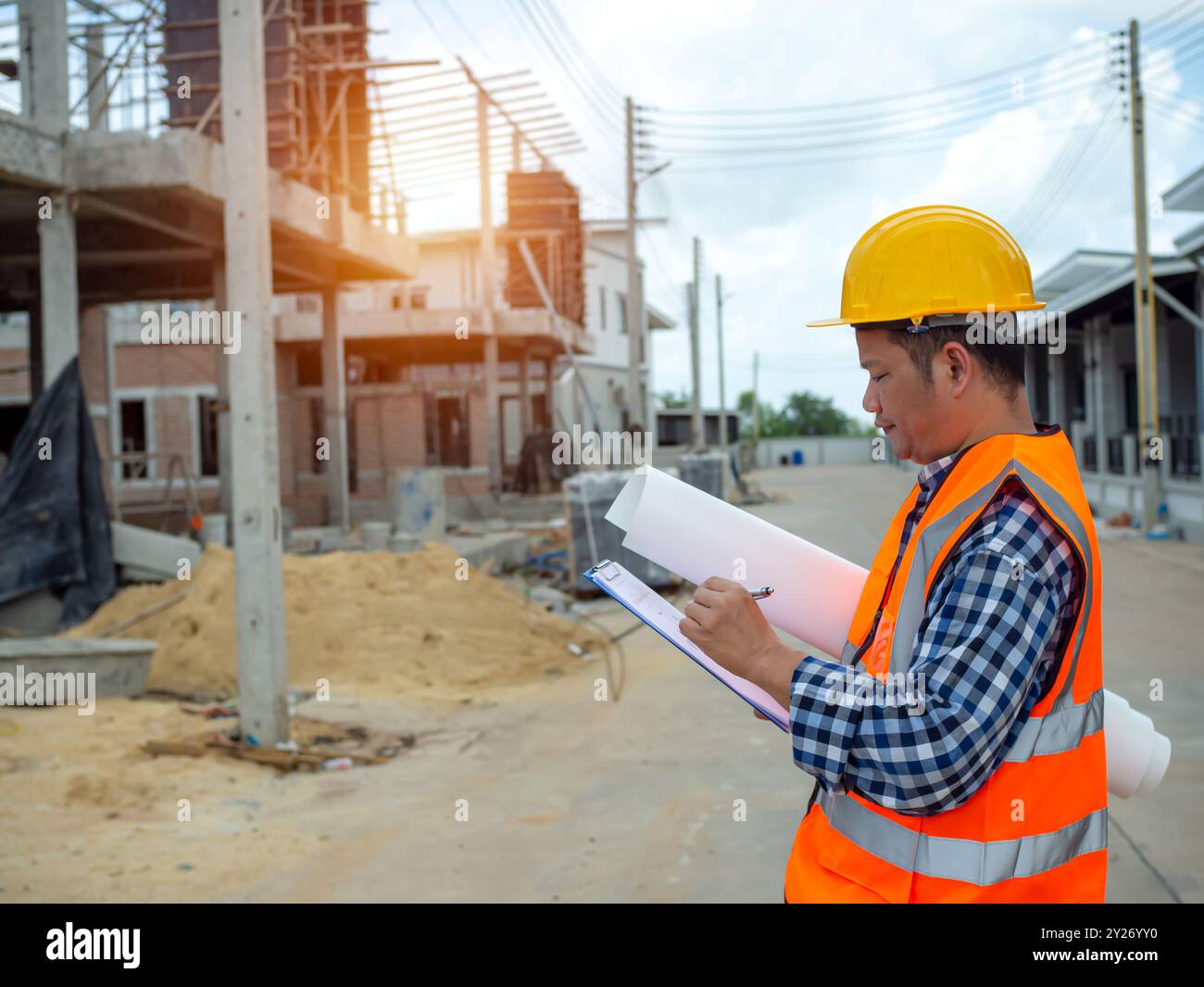 Engineers holding blueprint project working outdoors building side with ...