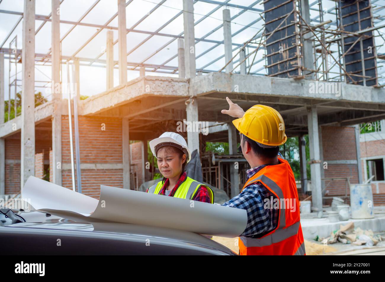 Team engineers holding blueprint project working outdoors building side with blueprints on a ...