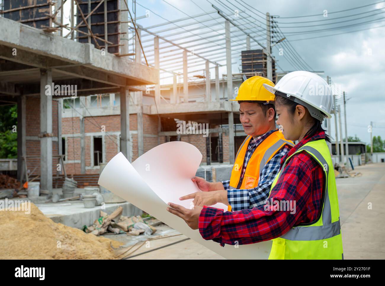 Team engineers holding blueprint project working outdoors building side with blueprints on a ...