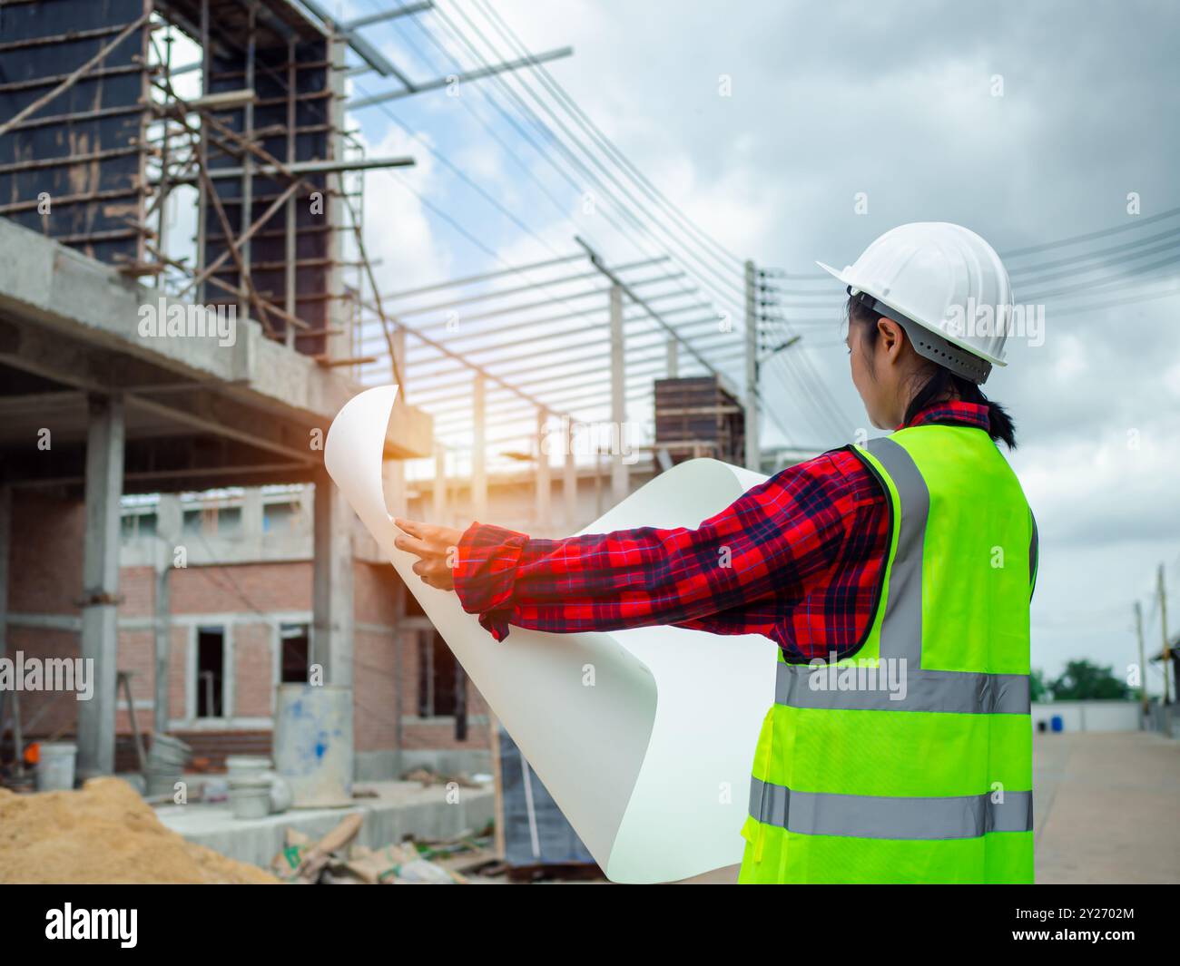 Engineers holding blueprint project working outdoors building side with ...