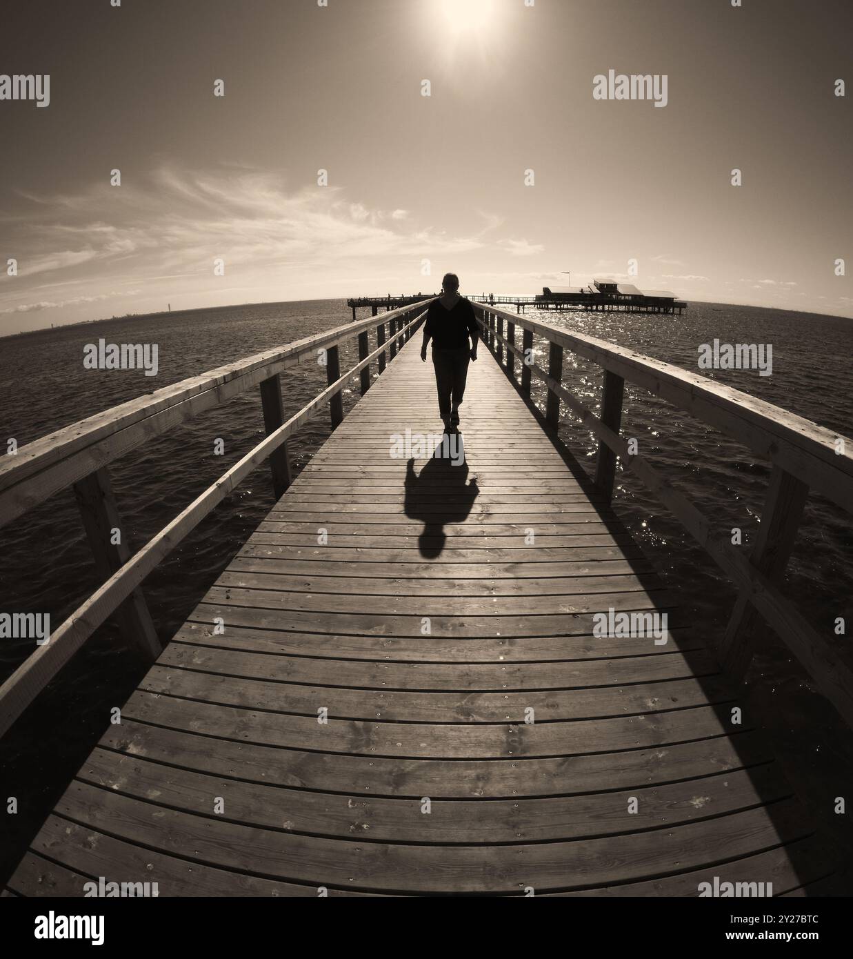 Woman in silhouette with shadow walking on long wooden jetty Stock ...