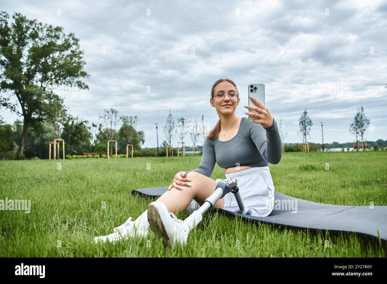 A young woman relaxes on a mat, capturing the moment outdoors with her ...
