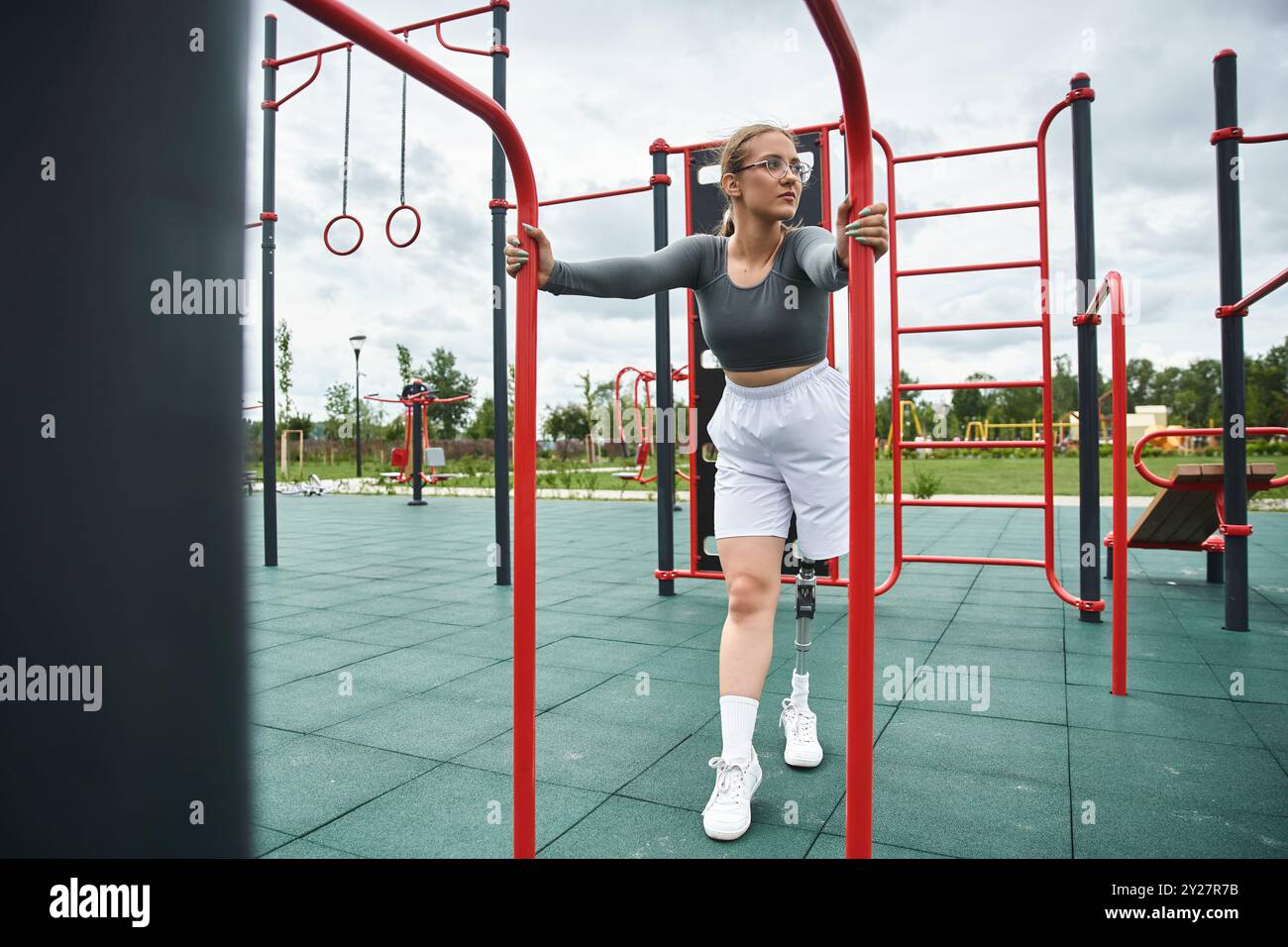 A determined young woman exercises outdoors, using her prosthetic leg ...