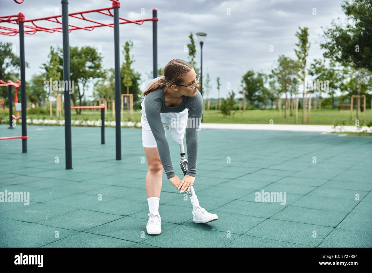 A young woman in sportswear stretches her prosthetic leg while enjoying ...
