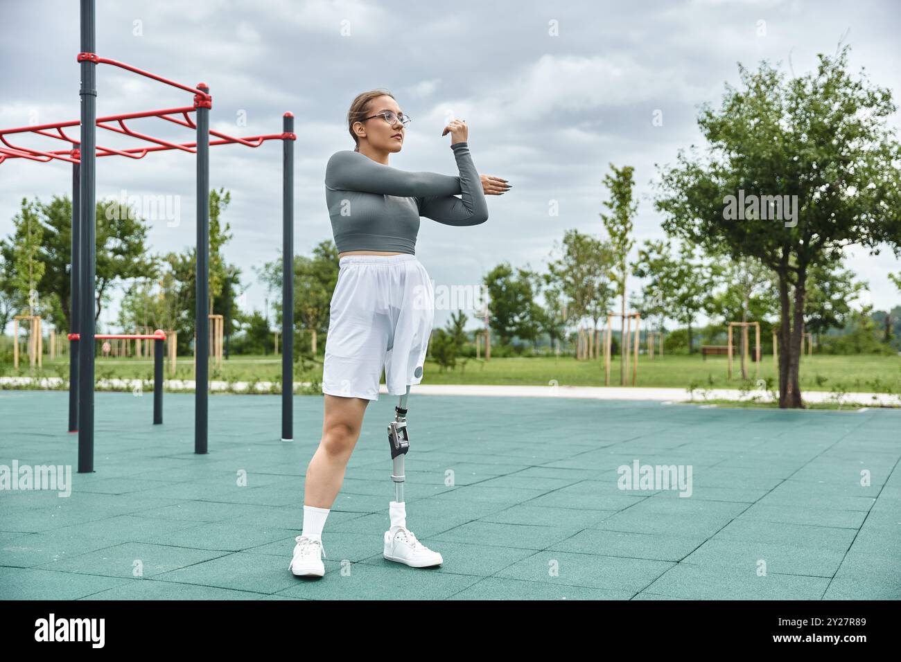 A determined young woman stretches her arms outdoors while embracing an ...