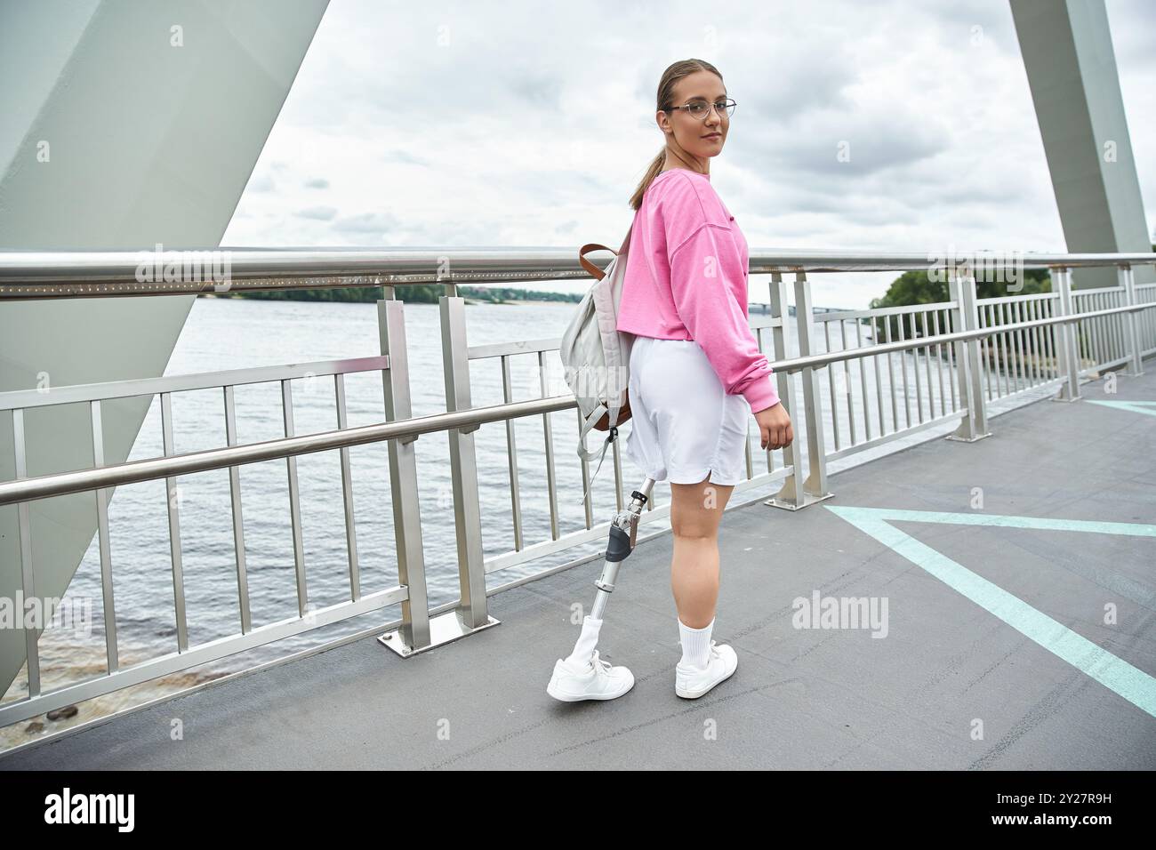 A young woman with a prosthetic leg embraces outdoor walk, confidently ...