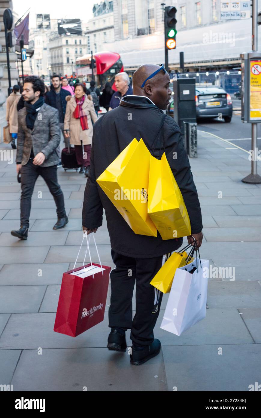 Shopping in London man with multiple colourful shopping bags walking in ...