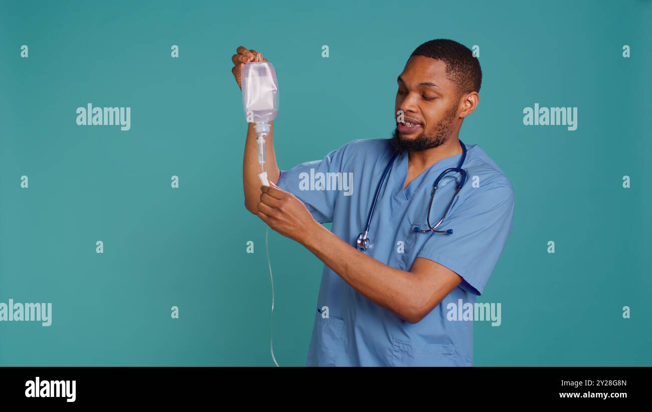 Male nurse holding IV bag, preparing to use it to administer fluids ...