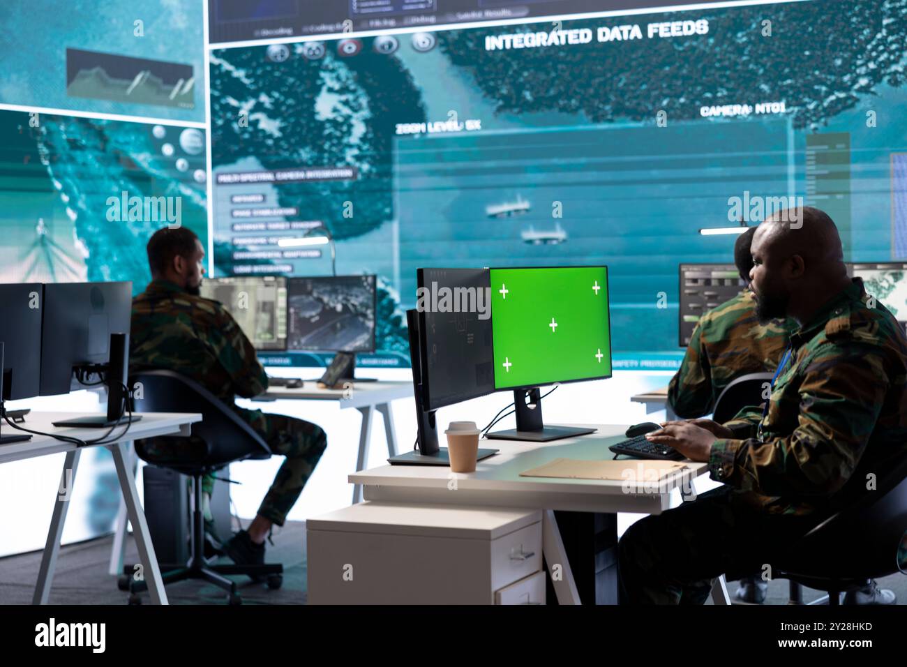 Soldier gathering real time surveillance data next to mockup display in high tech command center ...