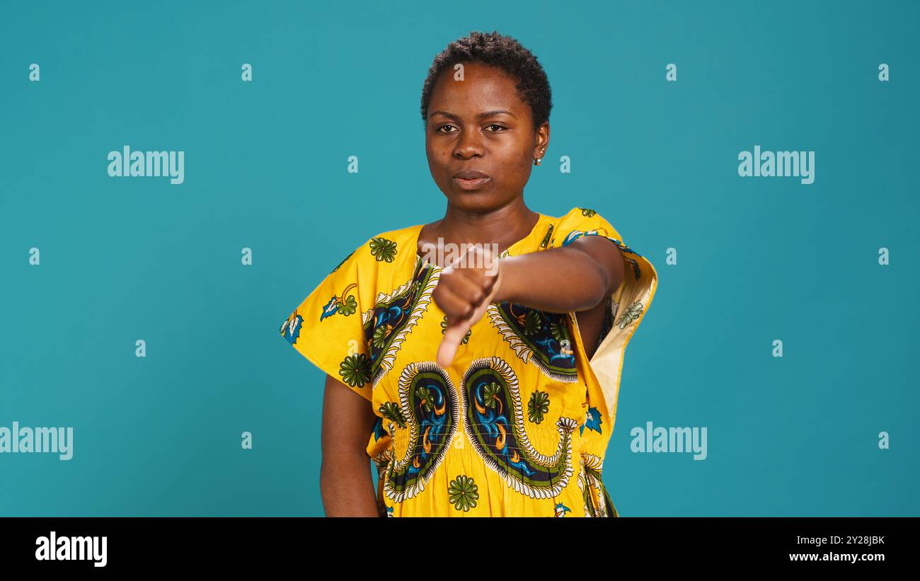 Displeased young woman giving thumbs down in studio, showing her ...