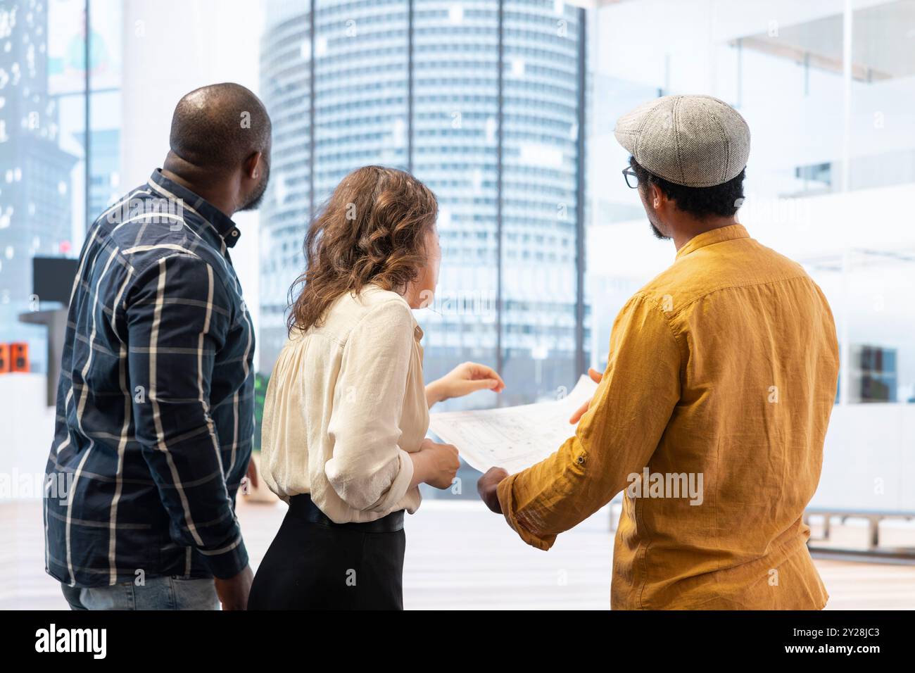 Real estate agent and clients discussing detailed blueprints for a new ...