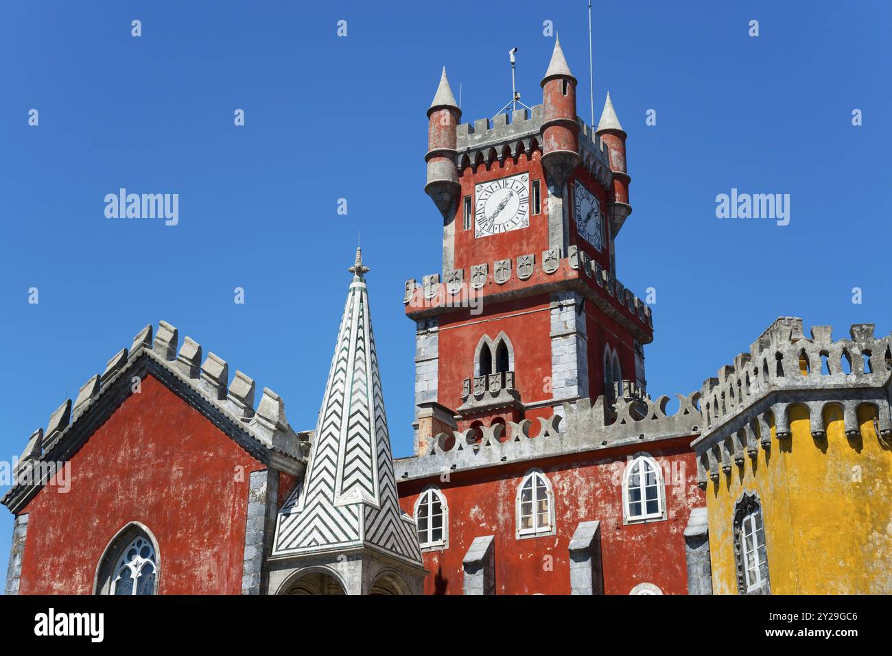 Red tower with clock and architectural decorations under a blue sky ...