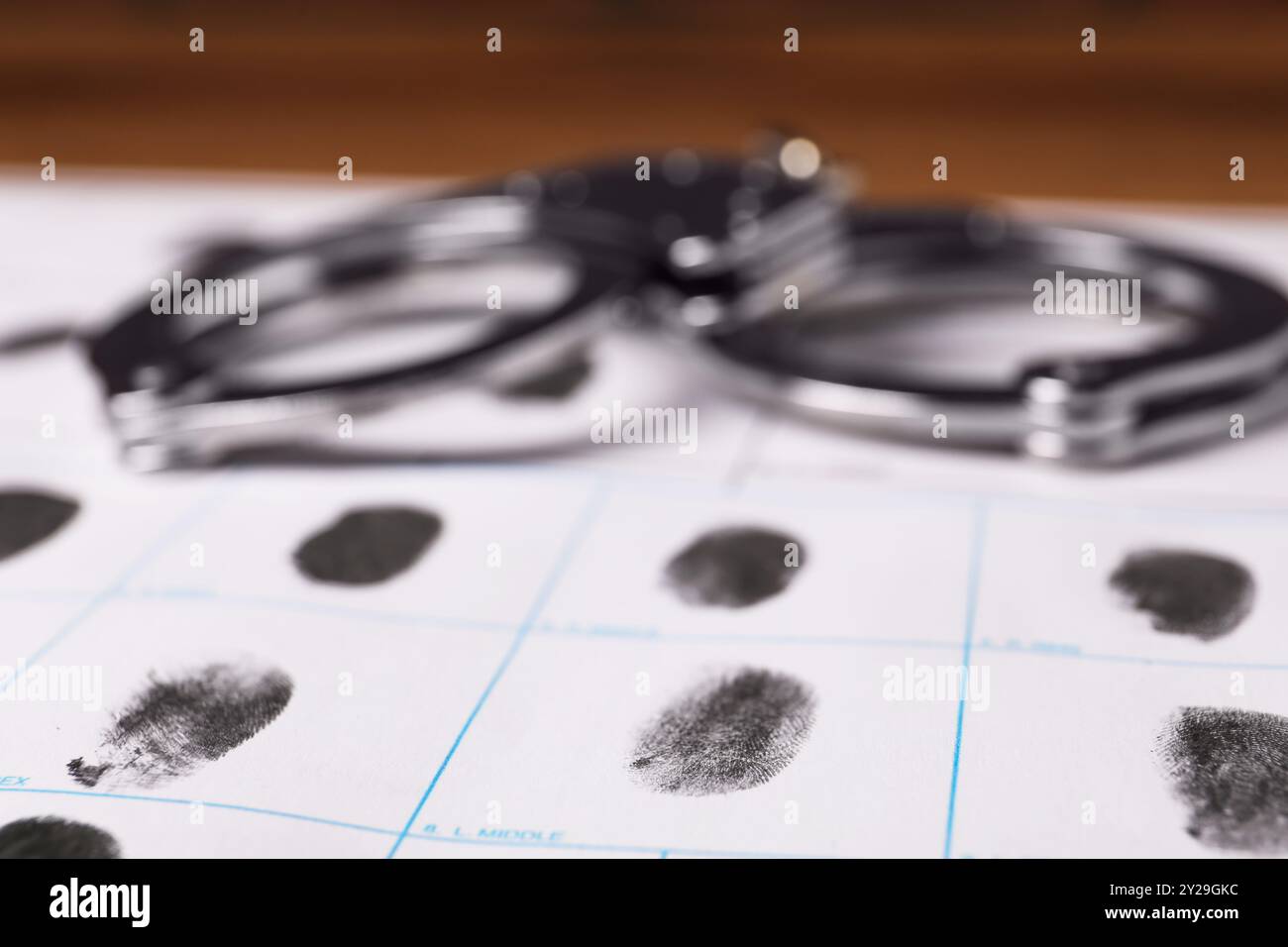 Paper sheet with human fingerprints and handcuffs on table, closeup ...
