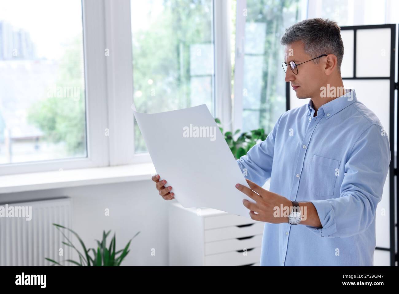 Architect holding paper sheet with engineering drawing in office Stock ...
