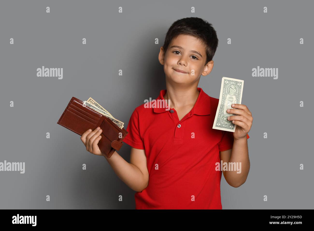 Cute boy with wallet and pocket money on grey background Stock Photo ...