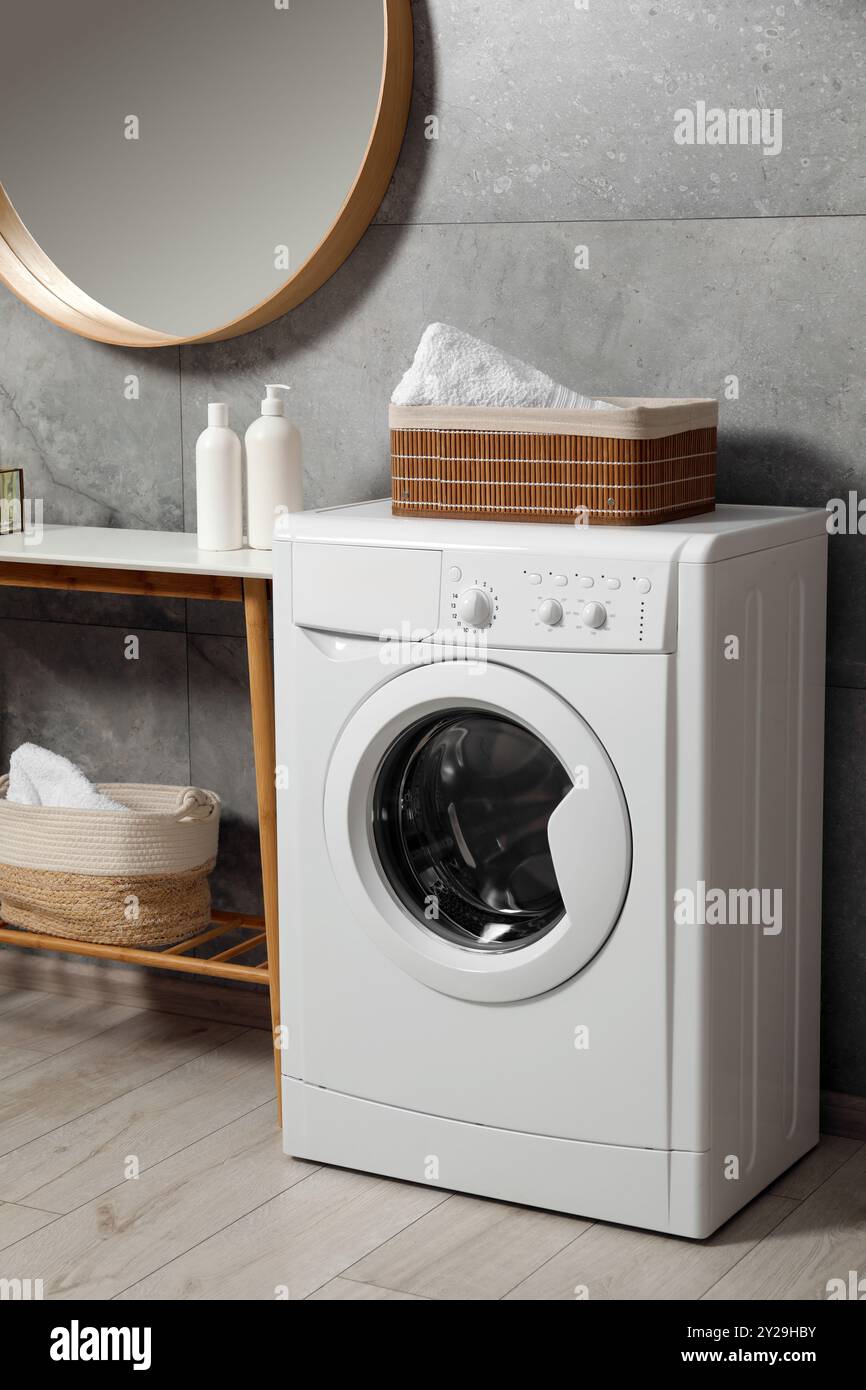 Washing machine, baskets with laundry and storage bench indoors Stock ...