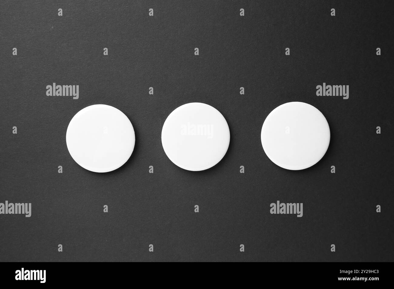 Blank white button badges on black background, top view. Mockup for ...