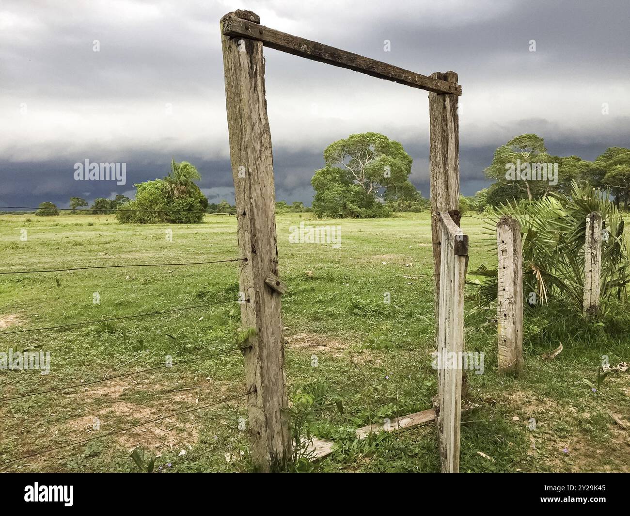 View through a wooden fence gate to typical pasture land with cloudy ...