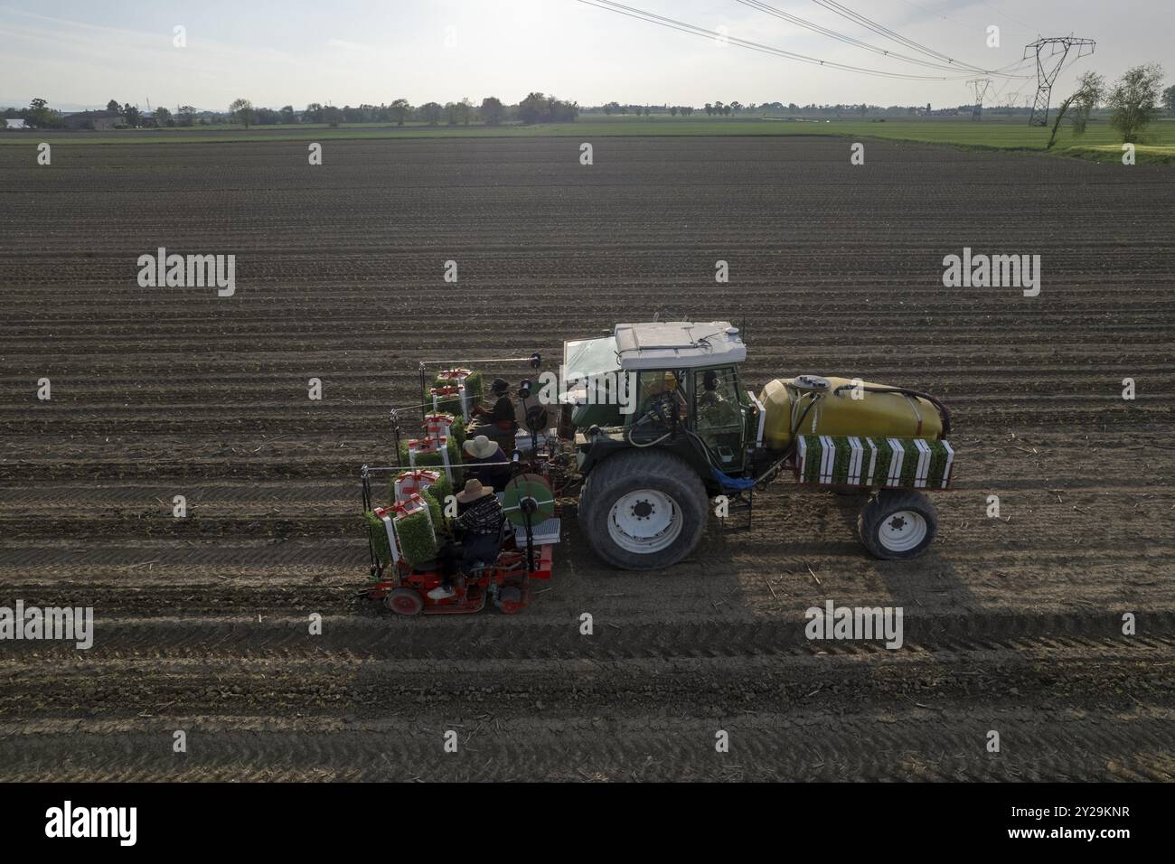 Aerial view of tractor planting tomato seedlings in vast field ...
