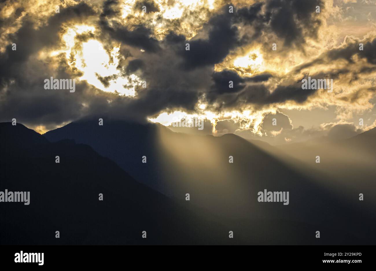 Mystical mood with sun behind dark clouds, sun rays falling over a dark ...