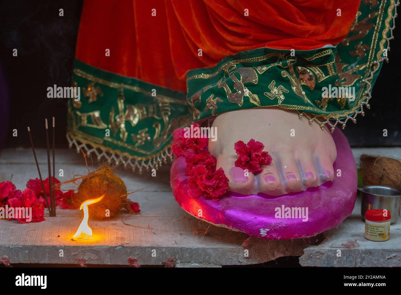 Flowers, incense sticks and a coconut are kept as offerings at the feet ...
