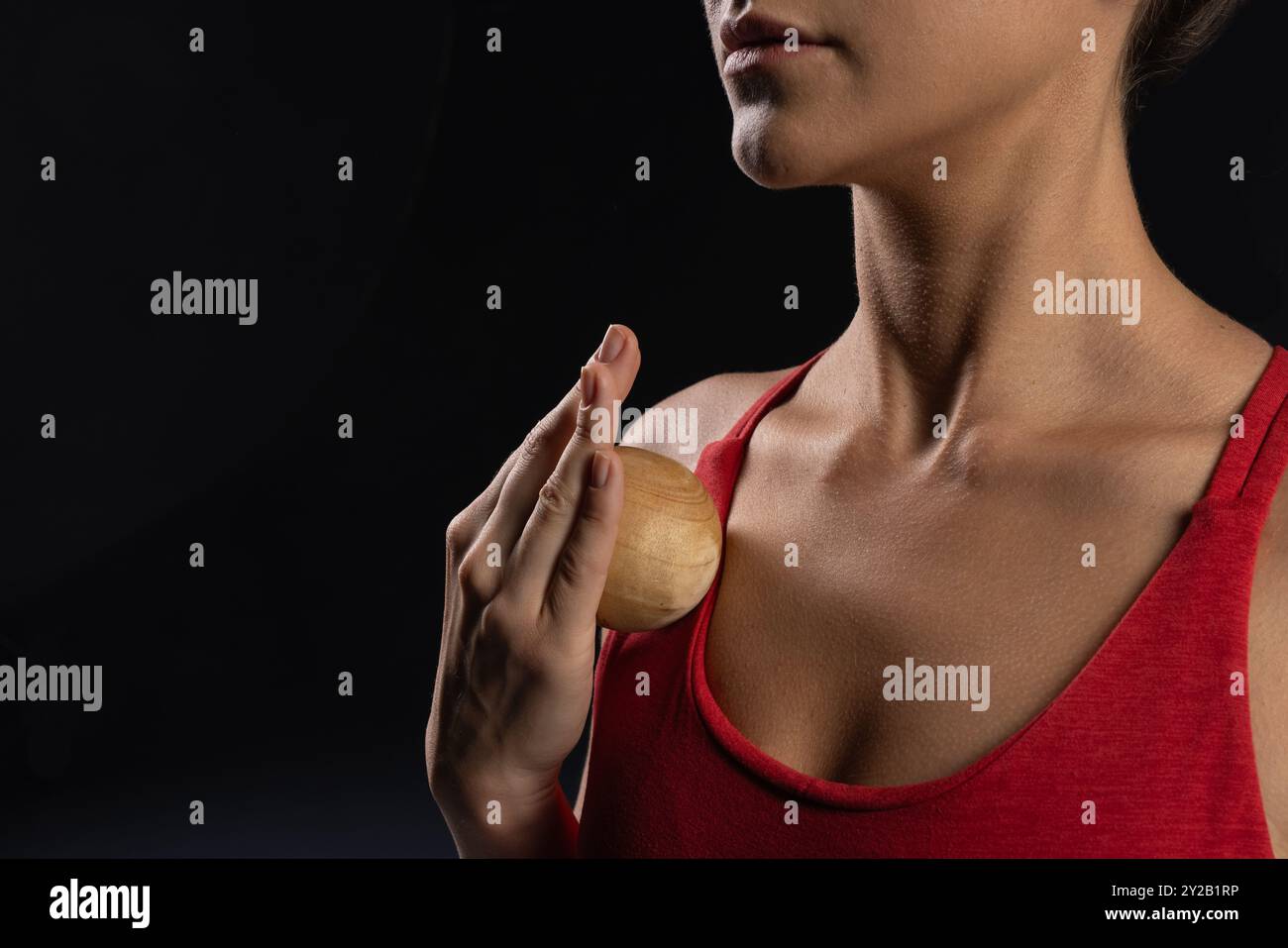 Close up of woman using wooden massage ball on chest wearing red tank ...
