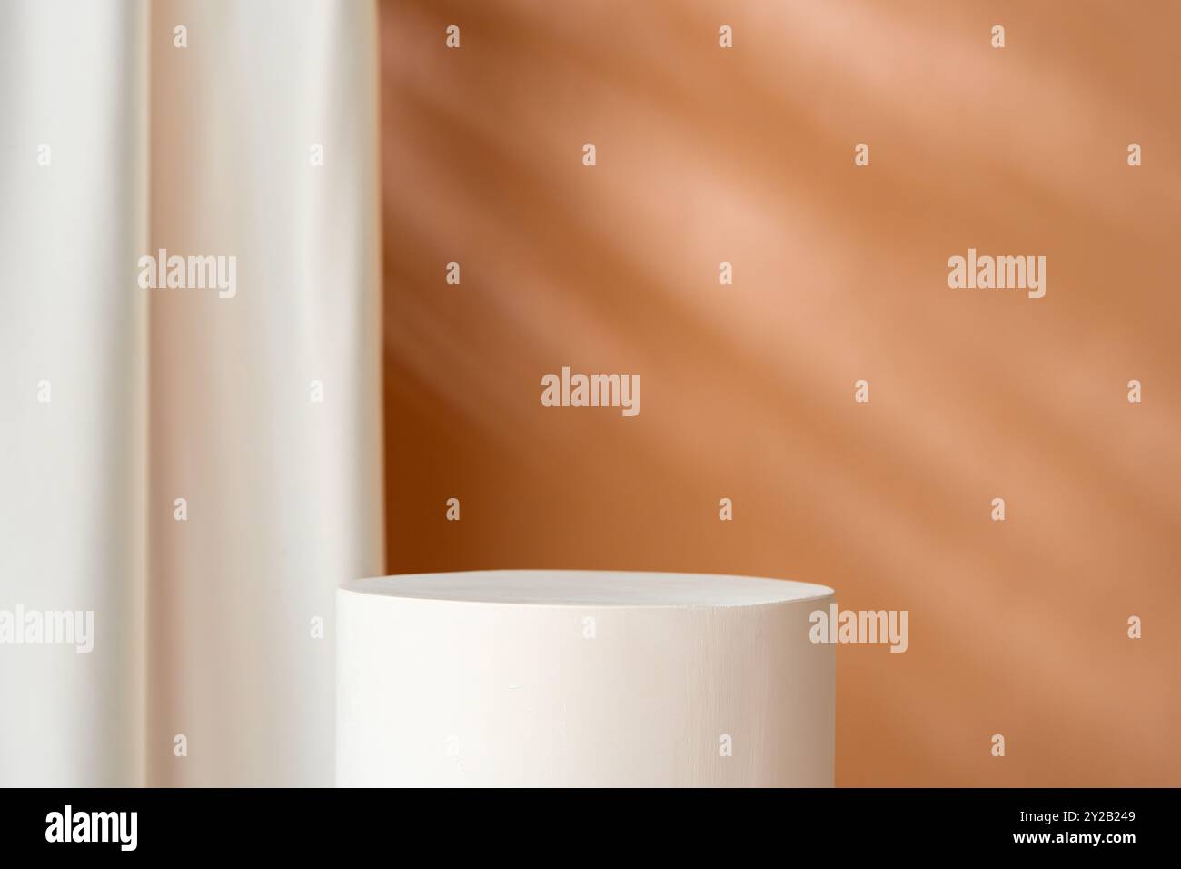 Minimalist decor featuring a white cylinder and draped fabric in a warm ...