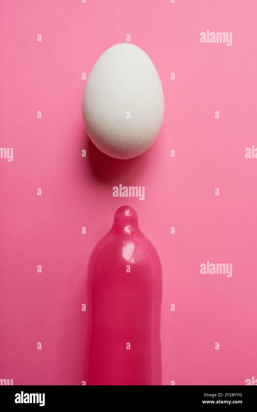 Egg, condom and studio background as contraceptive for birth rate ...