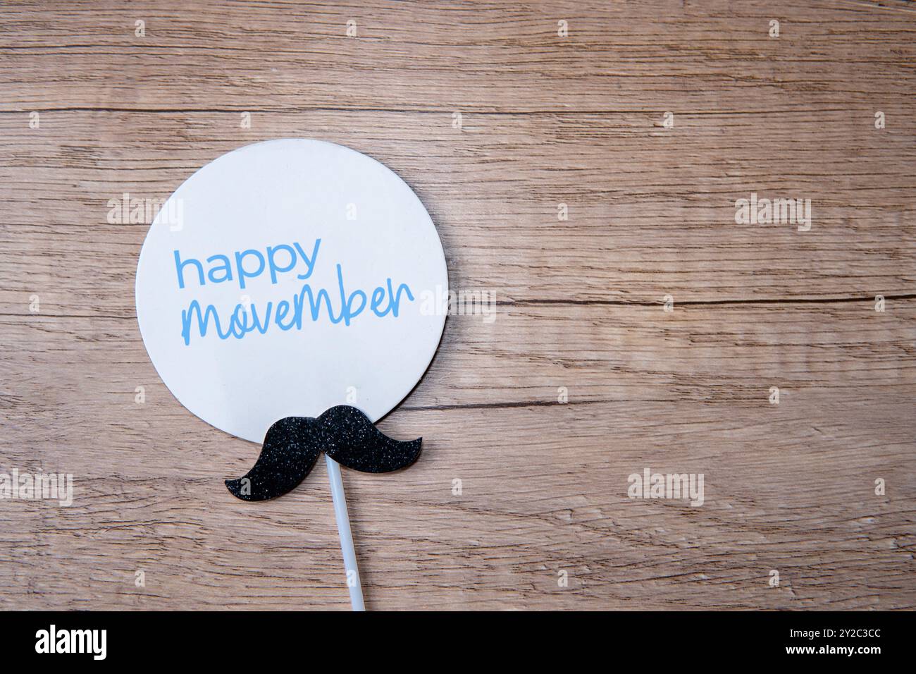 A white oval paper with the word “Happy Movember” attached to a stick ...
