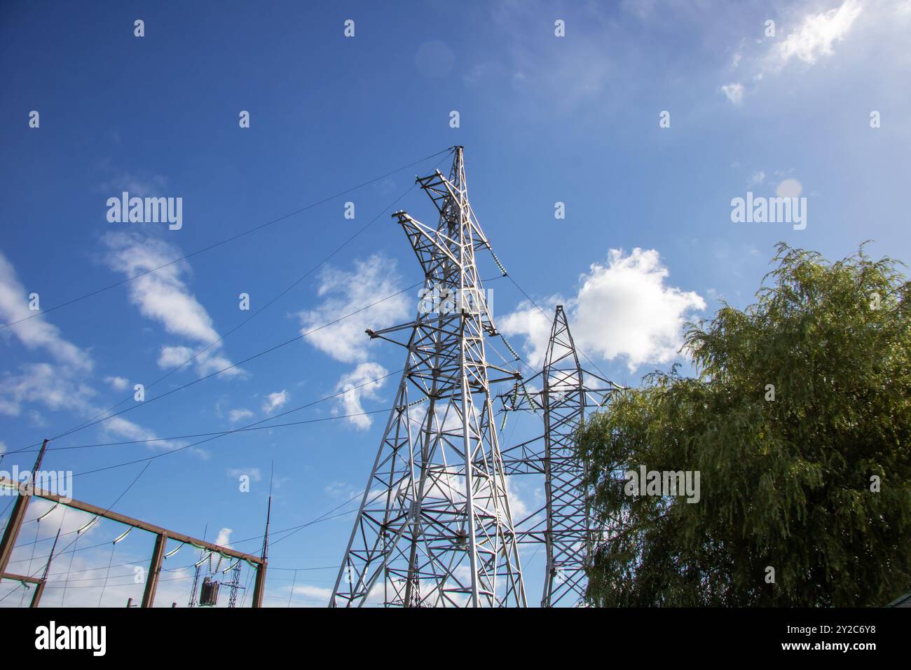 A tall power tower stands proudly with a vibrant blue sky as its ...