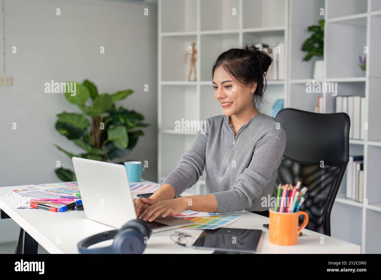Graphic designer typing on laptop with color palettes in office Stock ...
