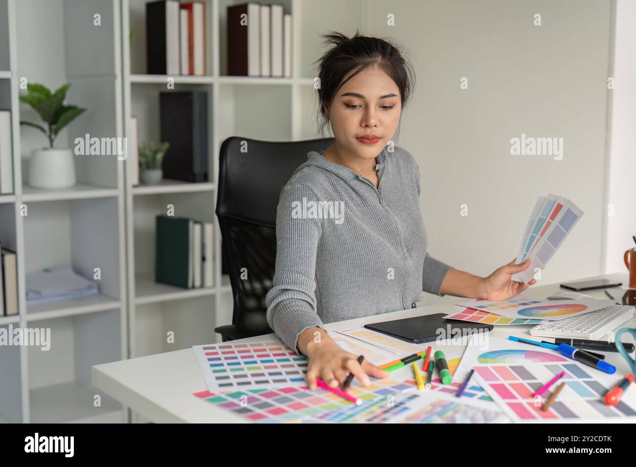 Graphic designer analyzing color swatches at desk Stock Photo - Alamy