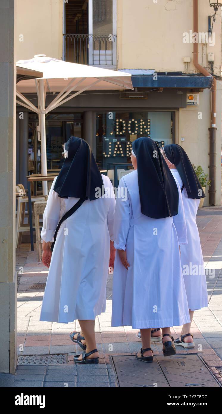 Three female nuns in traditional religious habits walking in the street ...