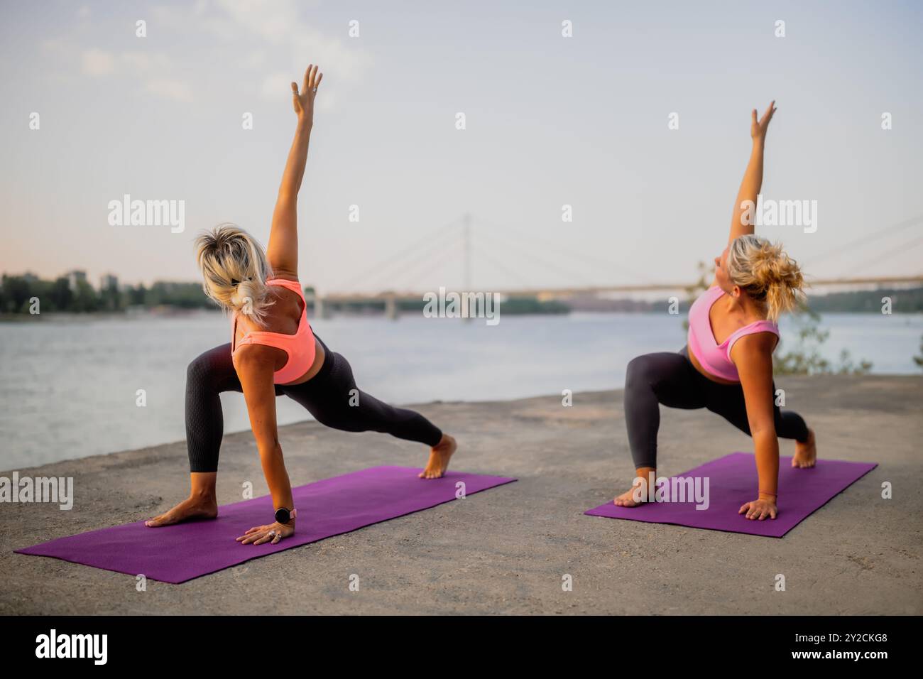 Two women practicing yoga outdoor in the city. Trikonasana, Bikram ...