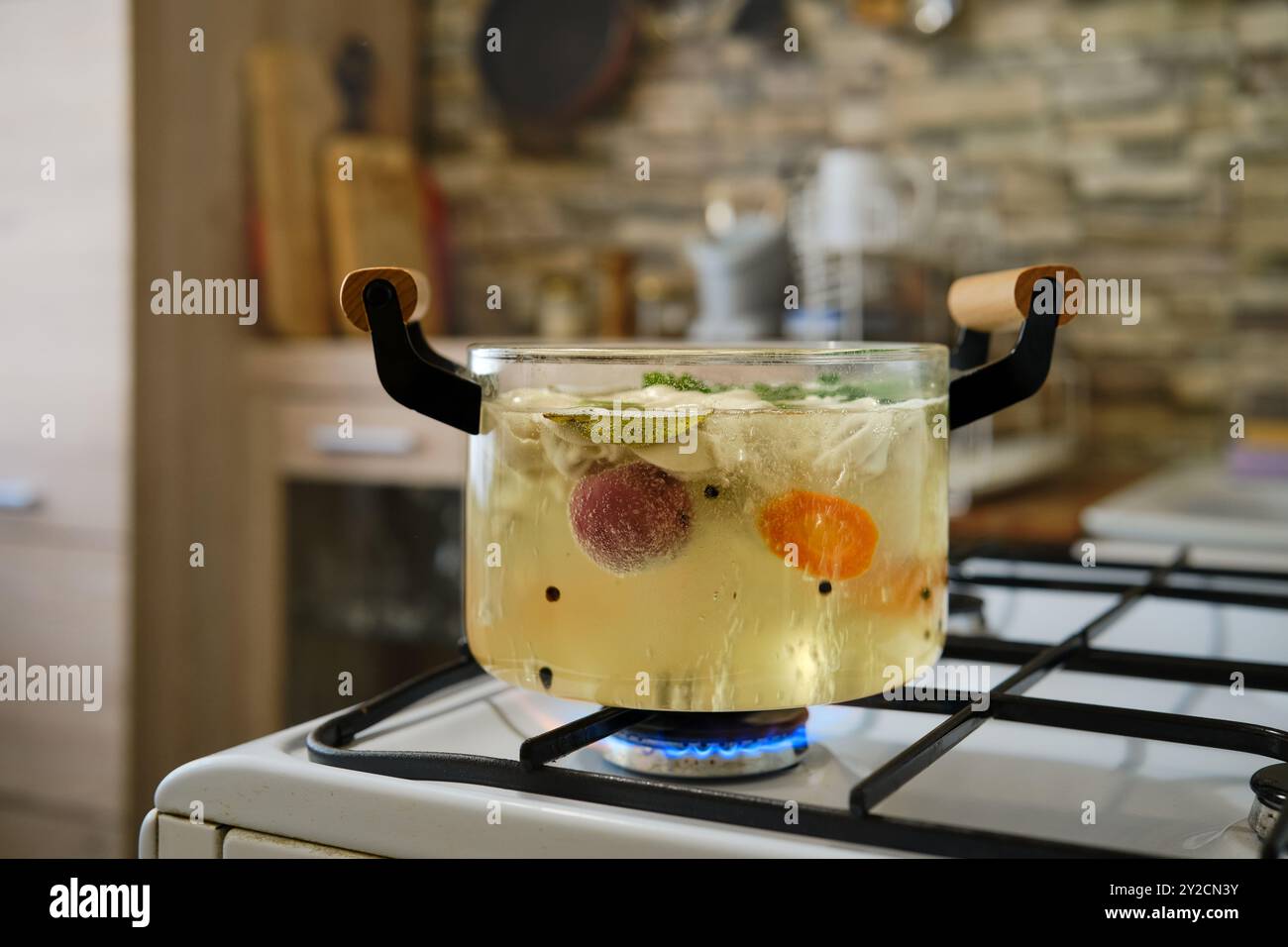 Cooking pelmeni in boiling vegetable broth in transparent saucepan on ...