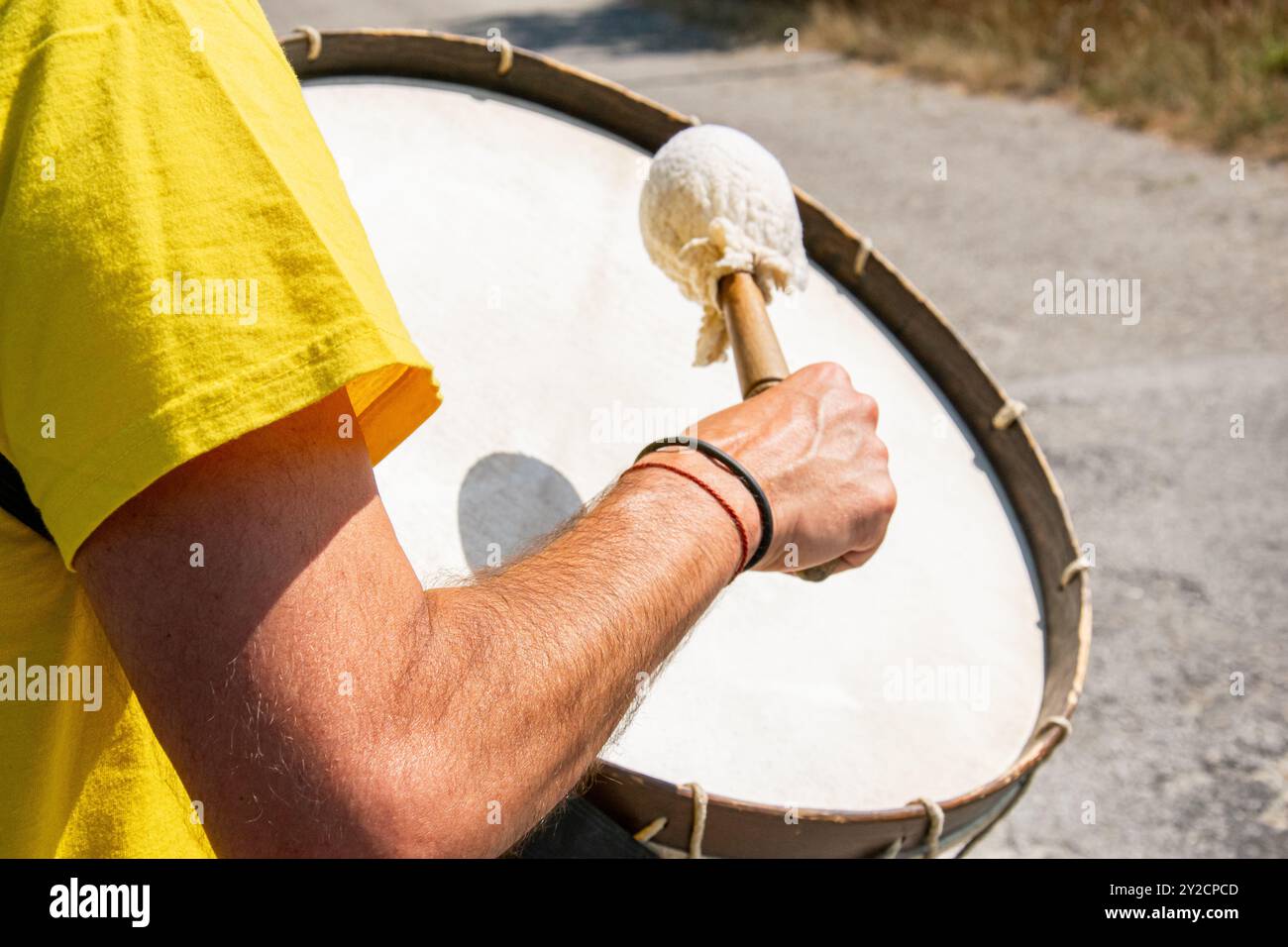 arm of a man in a yellow T-shirt playing a bass drum Stock Photo - Alamy