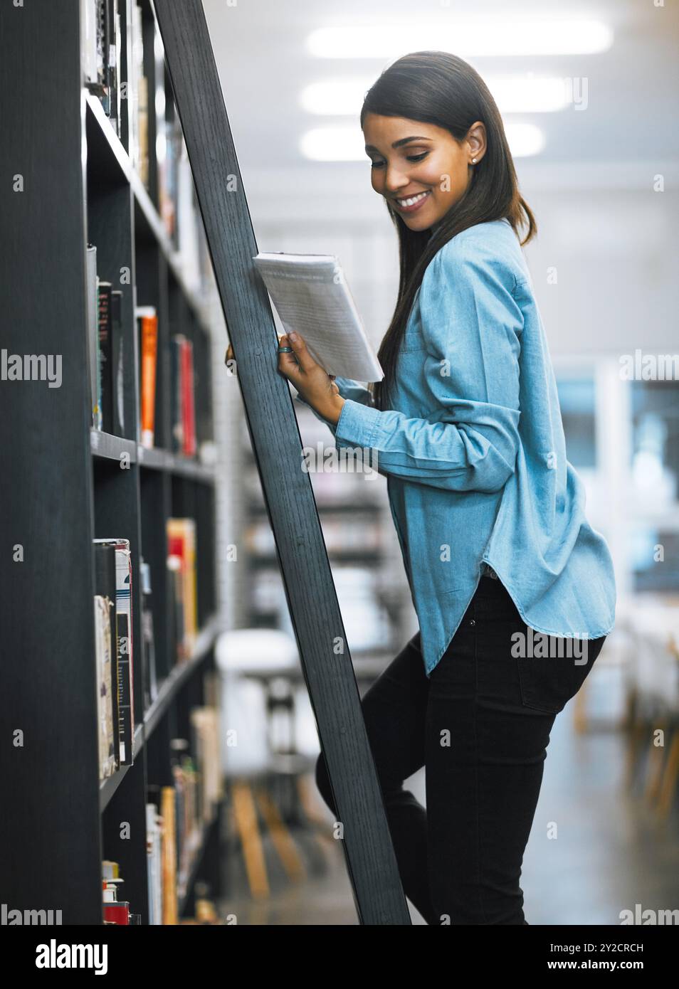 Woman, university student and library on bookshelf with ladder for text ...