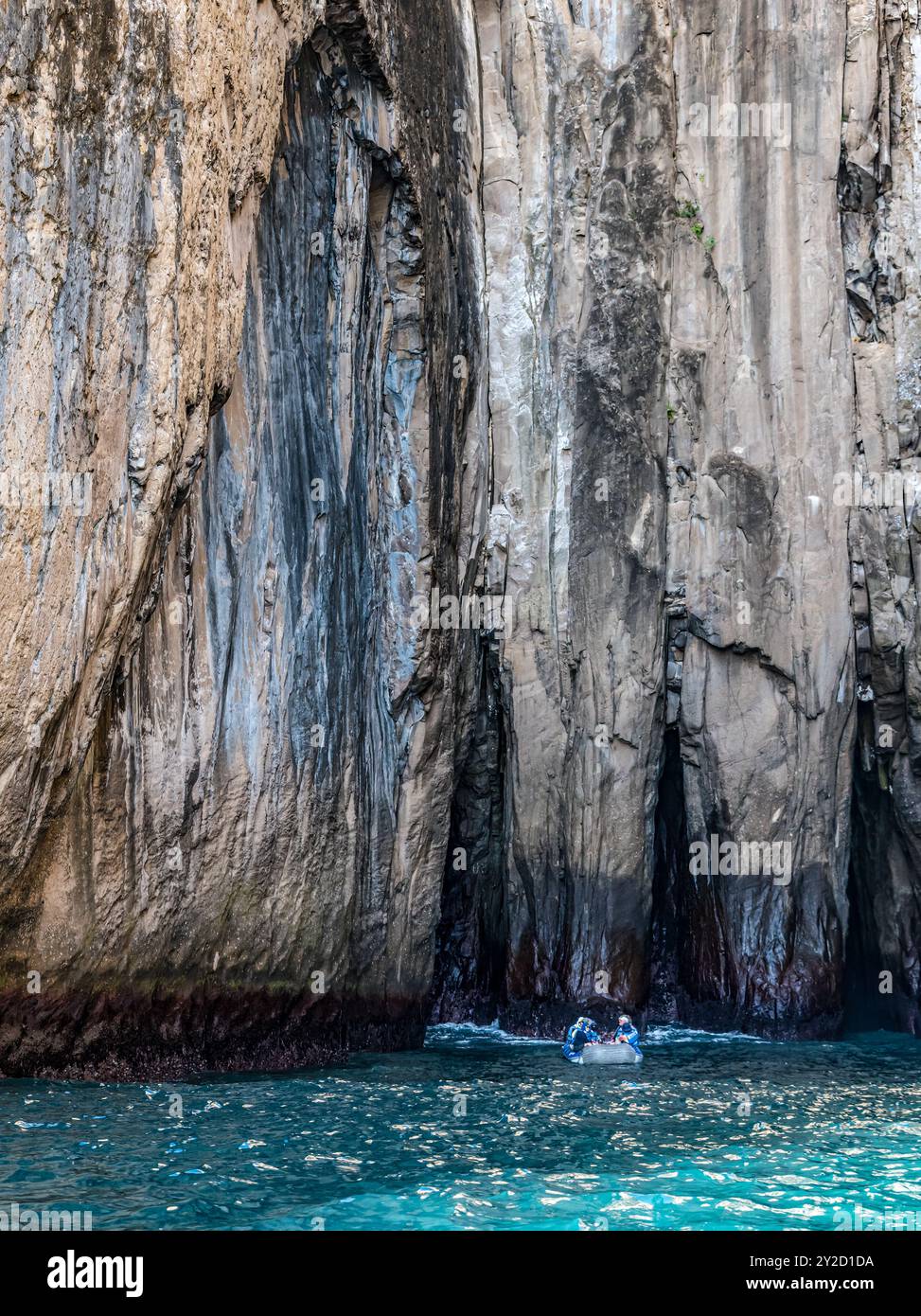 Small dinghy with people next to steep high rock face cliffside, San ...