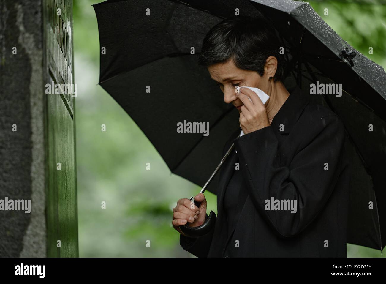 Side view of senior woman grieving next to memorial monument at grave ...