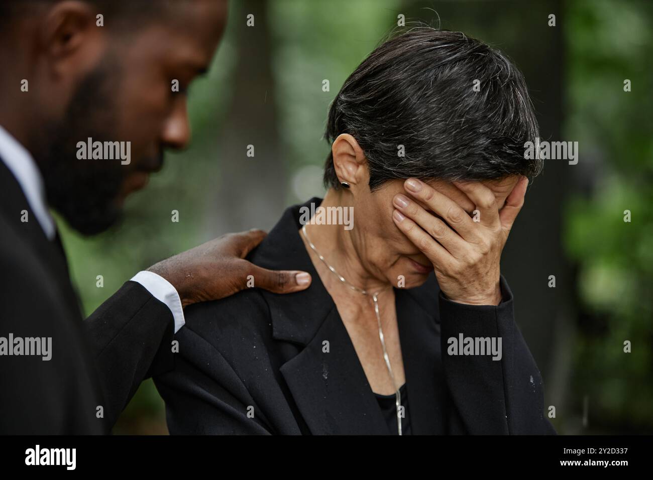 Medium shot of senior woman in black suit covering face with hand ...