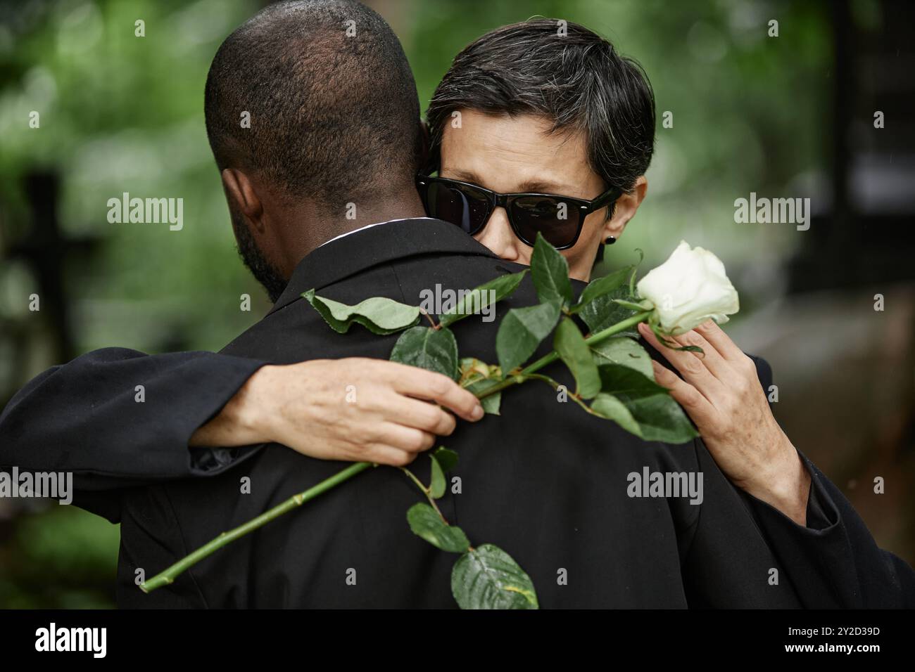 Medium shot of senior woman with white rose in hand giving comforting ...