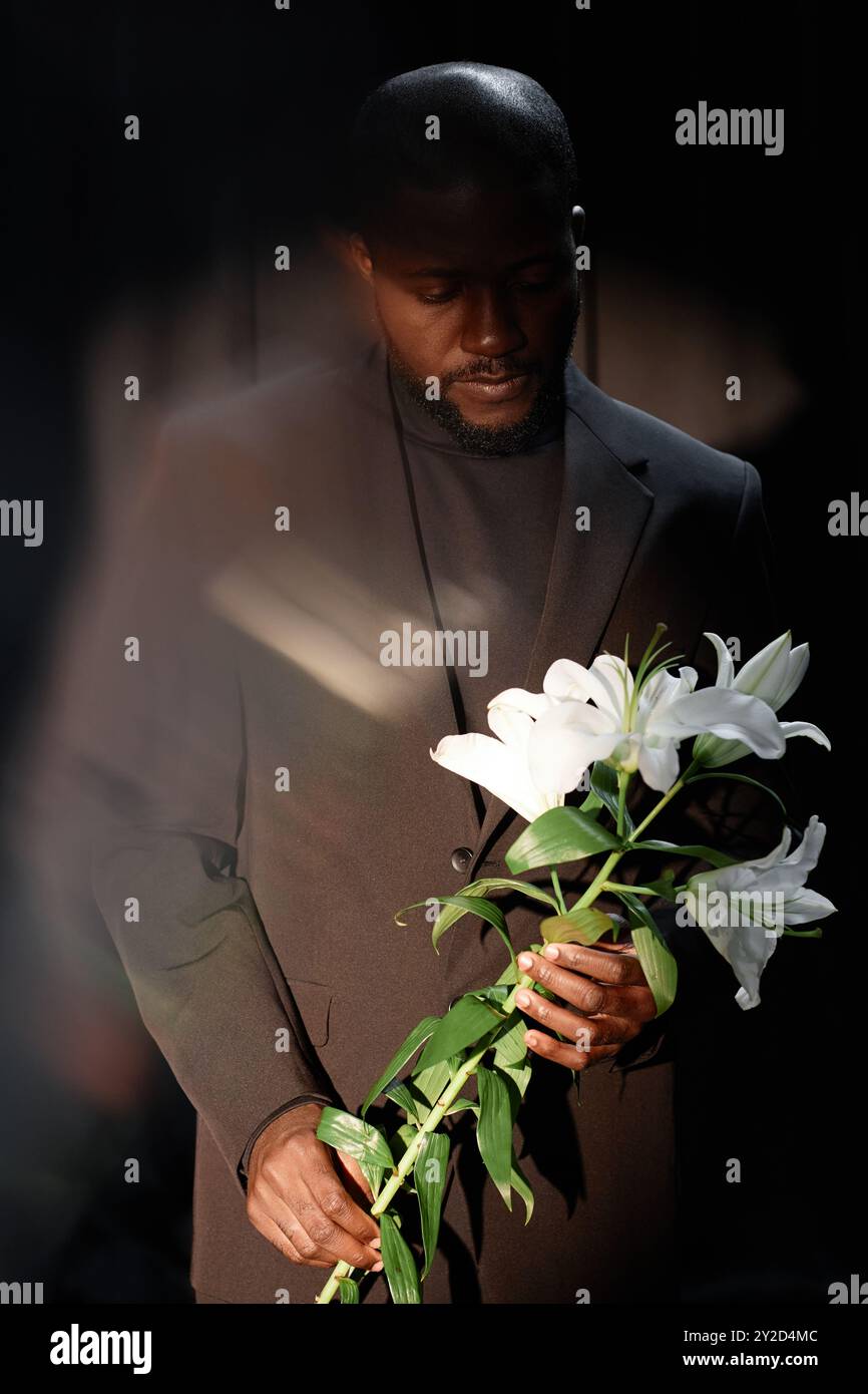 Vertical shot of pensive Black man in elegant suit holding delicate ...