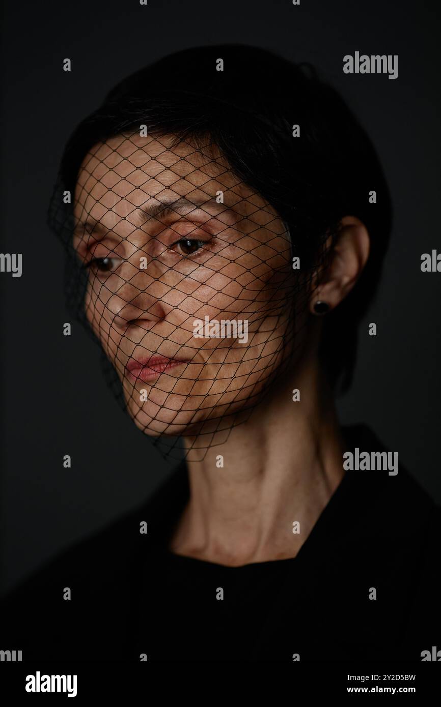 Vertical portrait with deep shadows of pensive senior woman wearing ...