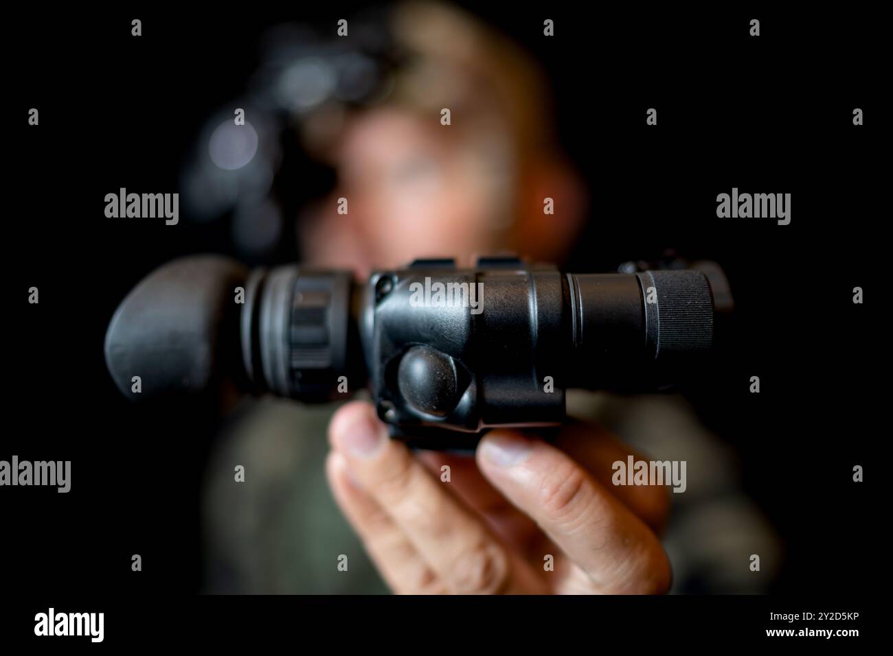 A special forces soldier iwith a night vision device in hand on a black ...