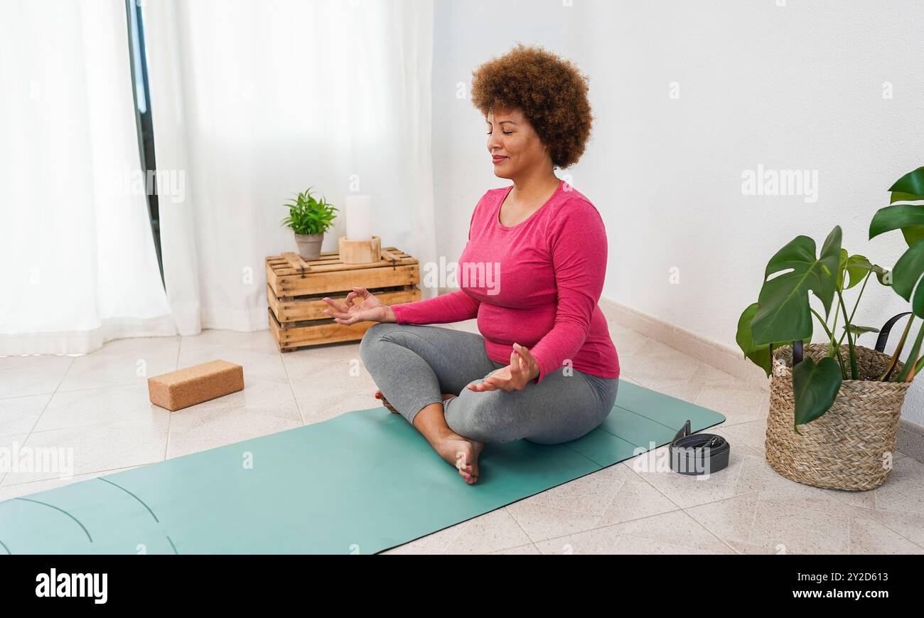African senior woman doing yoga session at home - Healthy lifestyle and ...