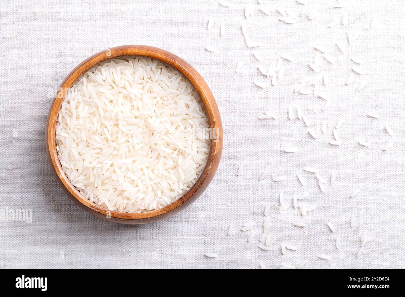 White basmati rice, in a wooden bowl on linen fabric. Grains of long ...