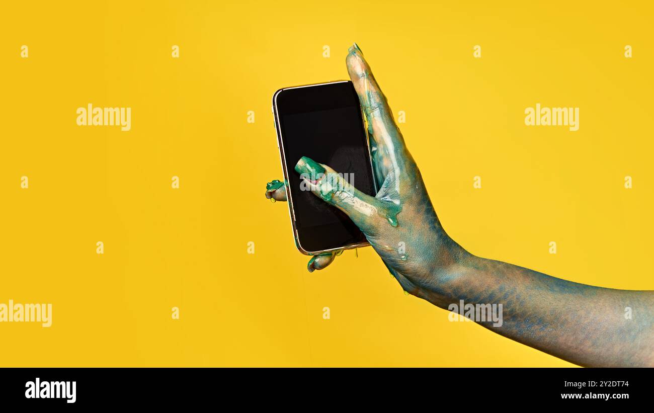 Hand covered in green slime holding black smartphone with blank screen ...