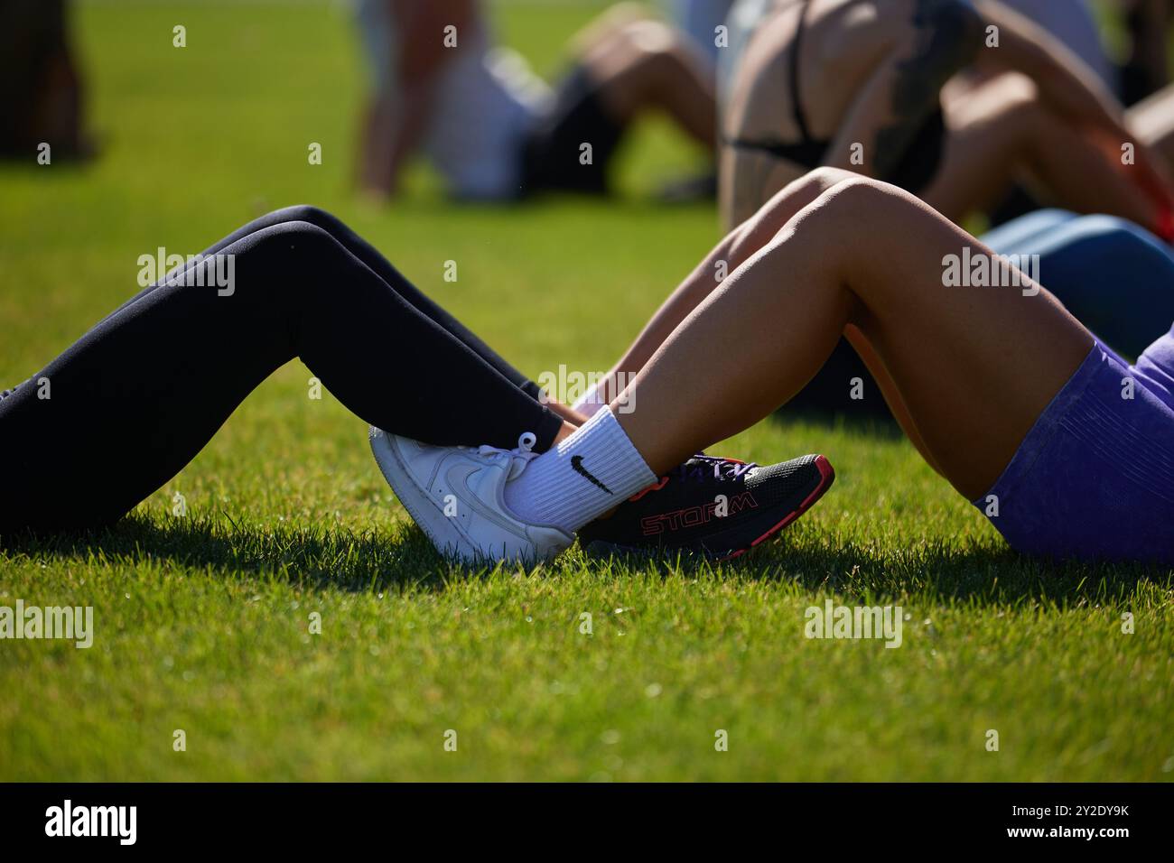 Feet of girls doing group workout routine outdoors. Athletes exercising ...