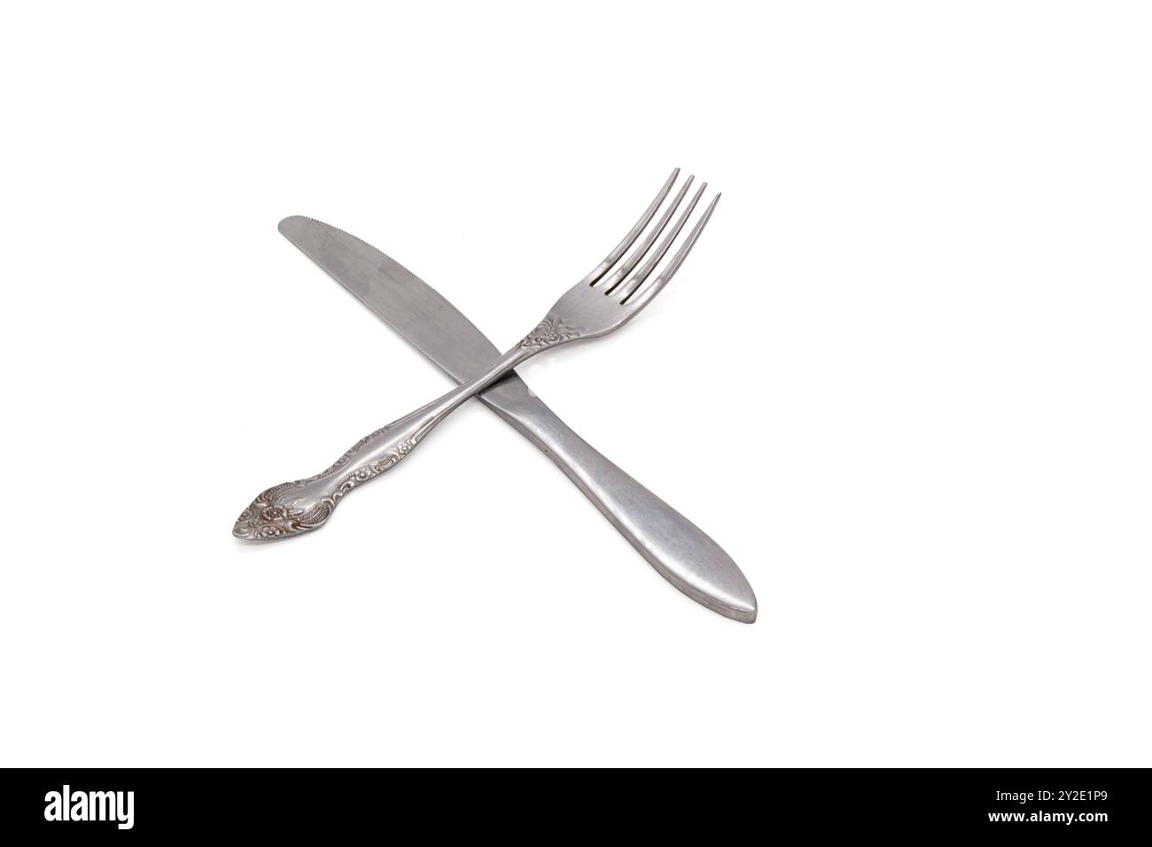 Metal fork and table knife lying crosswise on white isolated background ...